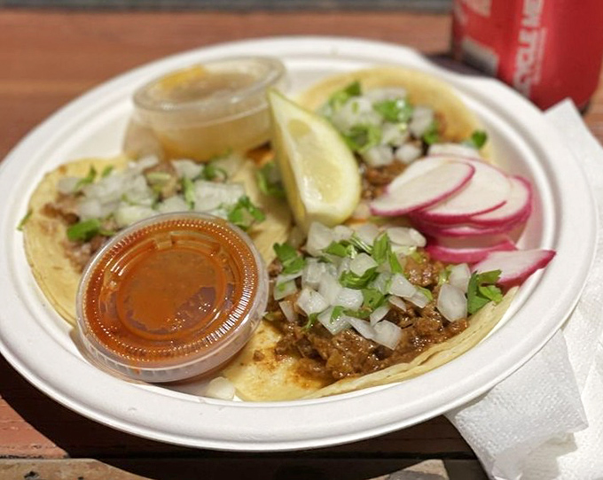 Al pastor tacos served with traditional garnishes and salsa—proof that sometimes the simplest pleasures deliver the most profound satisfaction.