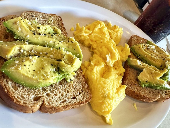Avocado toast that actually justifies the hype – perfectly ripe slices fanned across hearty bread with eggs that bring sunshine to the plate.