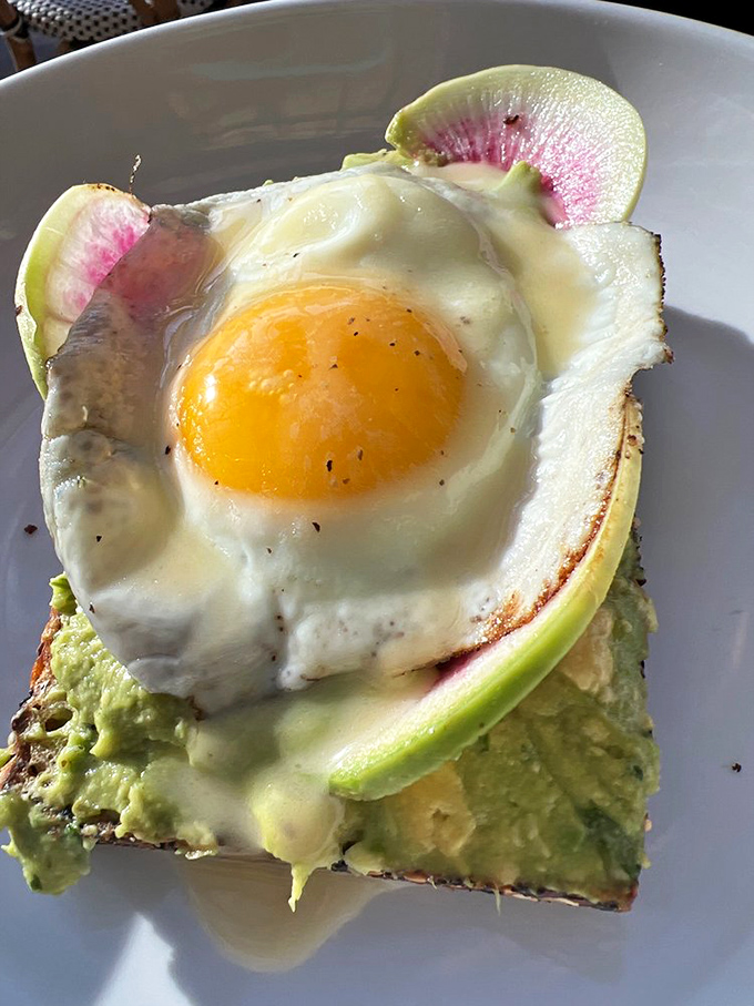 Avocado toast gets the royal treatment with watermelon radish and a sunny-side-up egg. This isn't breakfast; it's edible artwork.