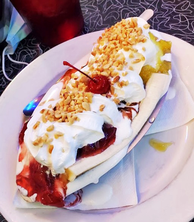 Banana split drowning in toppings so rich, it practically demands its own gravitational pull and worship.