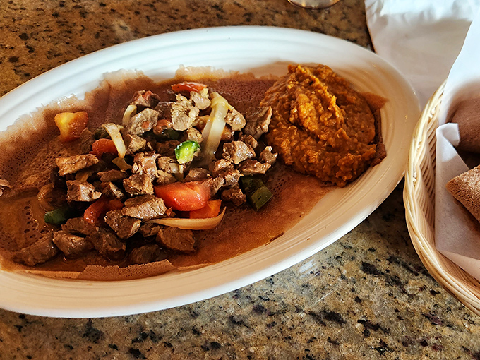 Beef Tibs&mdash;where tender meat meets vibrant vegetables on a bed of injera. This isn't just dinner; it's a tactile adventure for your hands and palate.