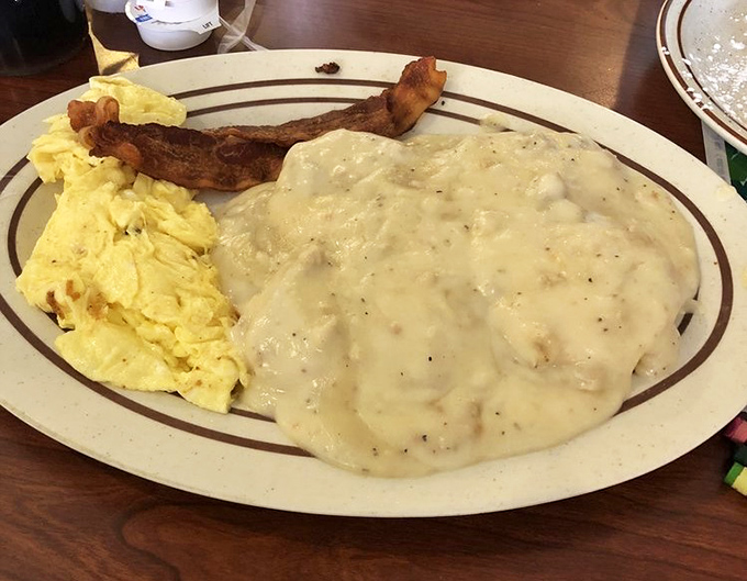Biscuits and gravy so creamy they could make a Southern grandma weep with joy, paired with fluffy scrambled eggs and a strip of bacon for good measure.
