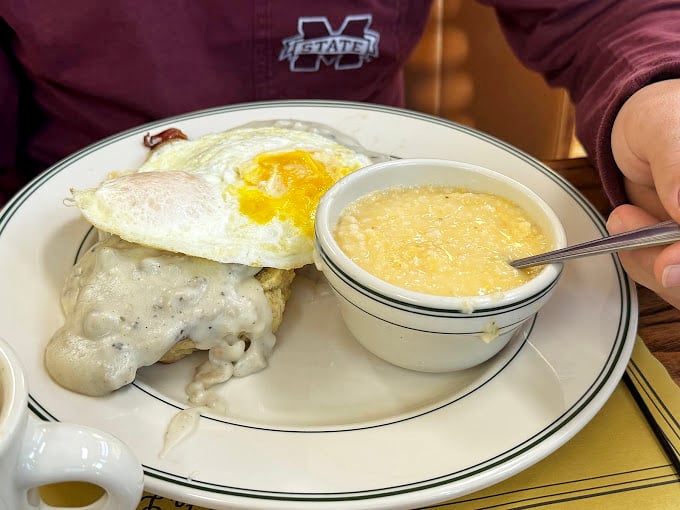 The holy trinity of Southern breakfast: perfectly runny egg, creamy grits, and sausage gravy that would make your cardiologist wince but your soul sing.