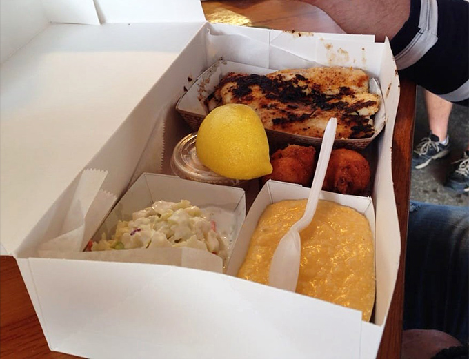 Blackened fish, golden hush puppies, and homestyle sides. This cardboard container holds more culinary joy than most white-tablecloth establishments could ever deliver.