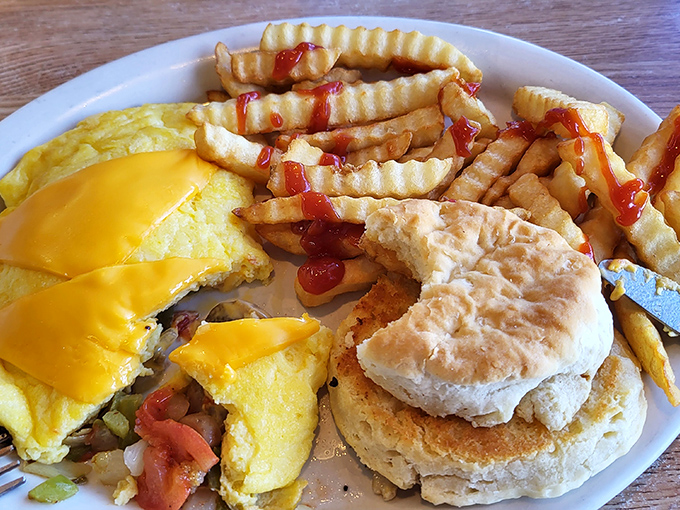 Western omelet, crinkle-cut fries, and a fluffy biscuit&mdash;the holy trinity of diner breakfast. That melted cheese blanket is performing acts of culinary kindness.