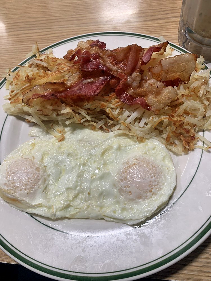 The holy trinity of breakfast perfection: crispy hash browns, bacon cooked just right, and eggs with yolks ready for their Instagram moment.