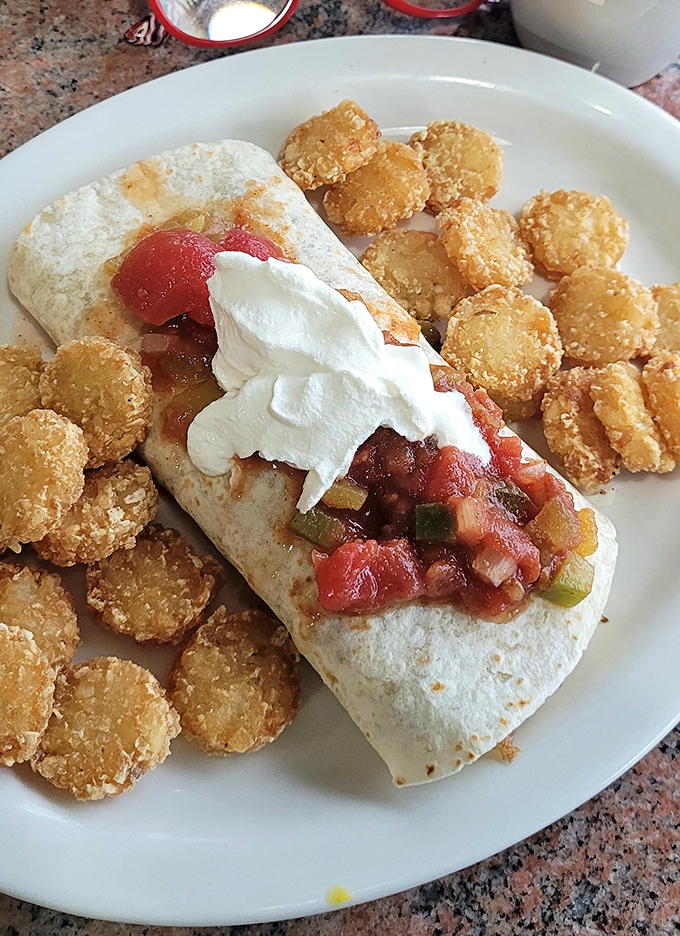 Behold the Breakfast Quesadilla in its natural habitat, surrounded by golden tater tots like delicious little bodyguards protecting their cheesy leader.