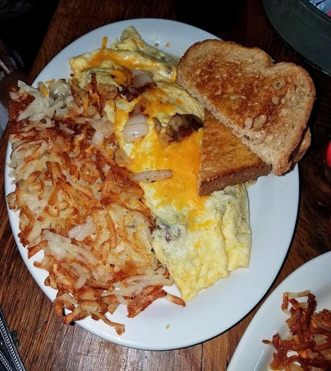 The breakfast trinity: golden hash browns, a perfectly folded omelet, and toast that's achieved that magical butter-soaked state of breakfast nirvana.