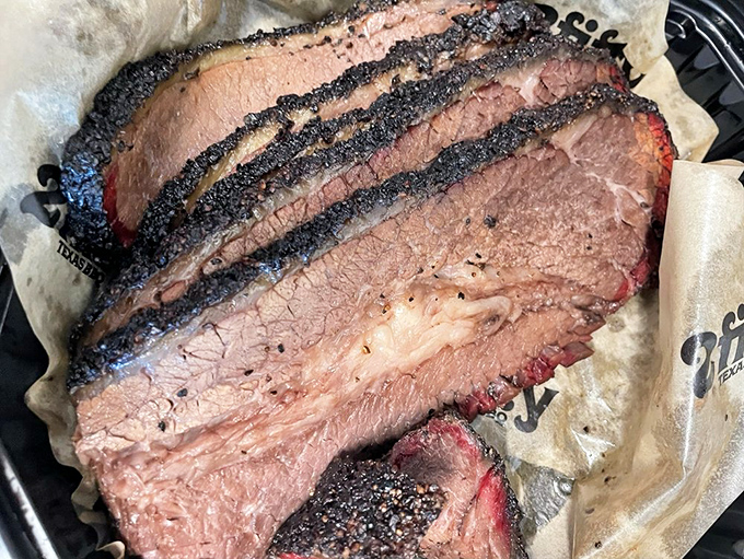 Brisket so tender it surrenders to gravity, sporting a smoke ring that would make Texas pitmasters nod in solemn respect.