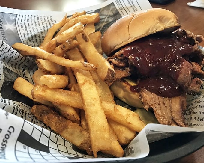 This brisket sandwich isn't just lunch; it's edible architecture with layers of smoky meat, tangy sauce, and golden fries standing guard.