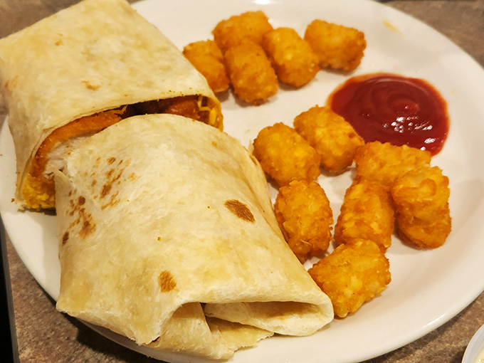 The Buffalo Chicken Wrap brings the heat without the fuss, nestled beside golden tater tots like a lunch special that graduated with honors.