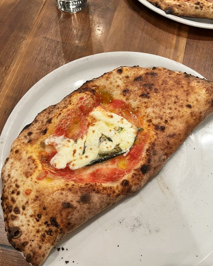 Not all calzones are created equal. This golden-brown masterpiece with its leopard-spotted crust promises a flavor explosion that delivers on first bite.