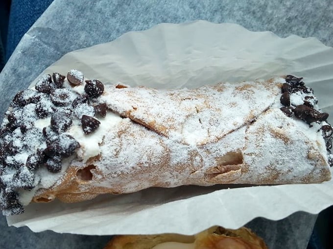 This isn't just any cannoli&mdash;it's a powdered sugar-dusted masterpiece with chocolate chips standing guard at both ends like sweet sentinels of satisfaction.