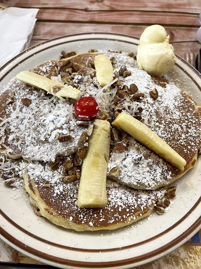 A pancake vacation for your taste buds&mdash;banana slices and pecans arranged like sunshine rays on a golden-brown horizon.
