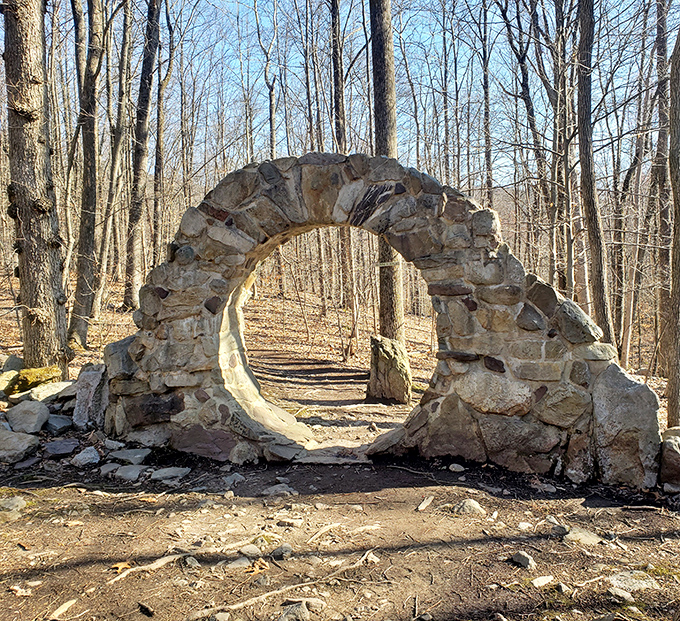 A perfect stone arch frames the forest path beyond. Nature's version of a portal to another dimension—no special effects budget required.