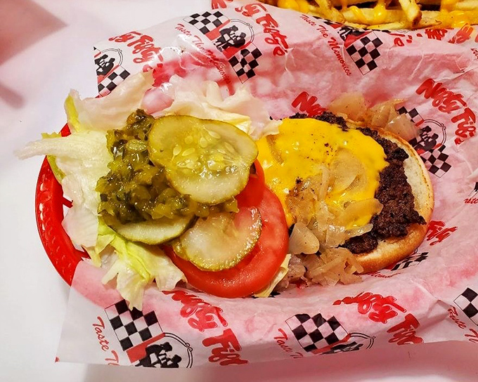 Behold the cheeseburger in its natural habitat—draped in melted American cheese with fresh veggies trying their best to make you feel virtuous.