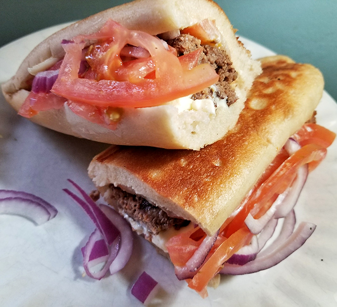 This isn't just a sandwich; it's architecture. Layers of meat, tomato, and onion creating the skyscraper of subs that demands a strategic first bite.