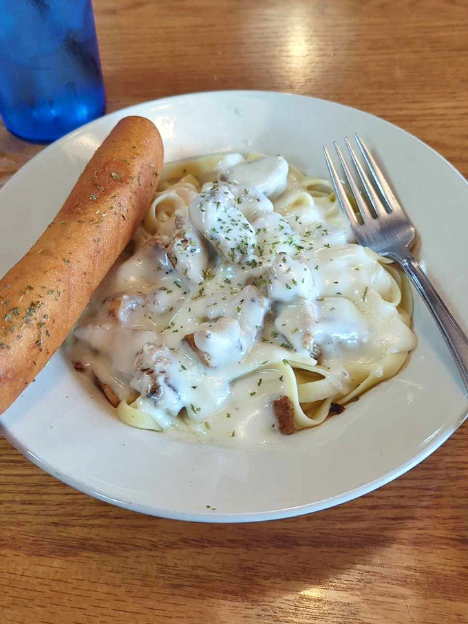 Fettuccine Alfredo with a breadstick that could double as a magic wand. This plate transforms "I'll just have a salad" into "I'll need a to-go box."