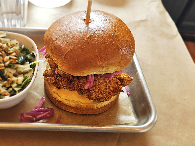 This isn't just a sandwich; it's architecture. The golden-fried chicken and vibrant pickled onions create a tower of flavor worth scaling.