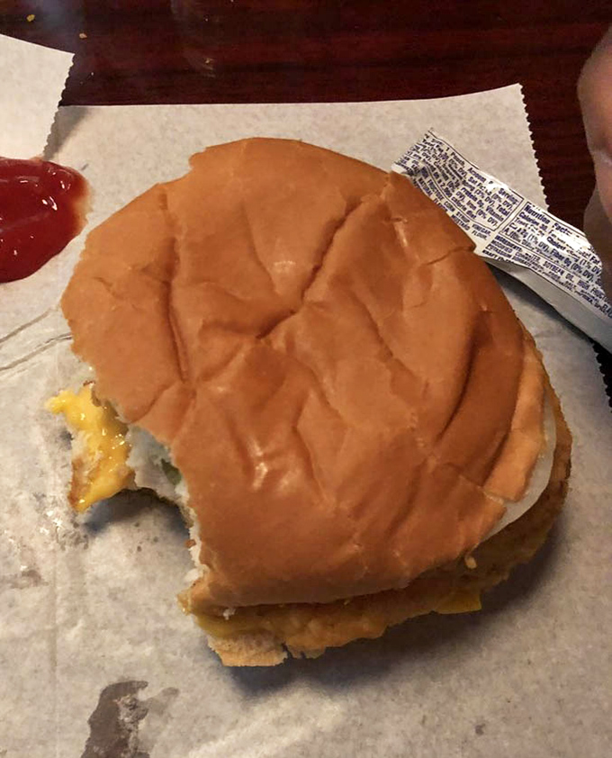 The chicken sandwich in its natural habitat &ndash; wax paper, melty cheese, and a bite already missing because waiting for photos was simply impossible.