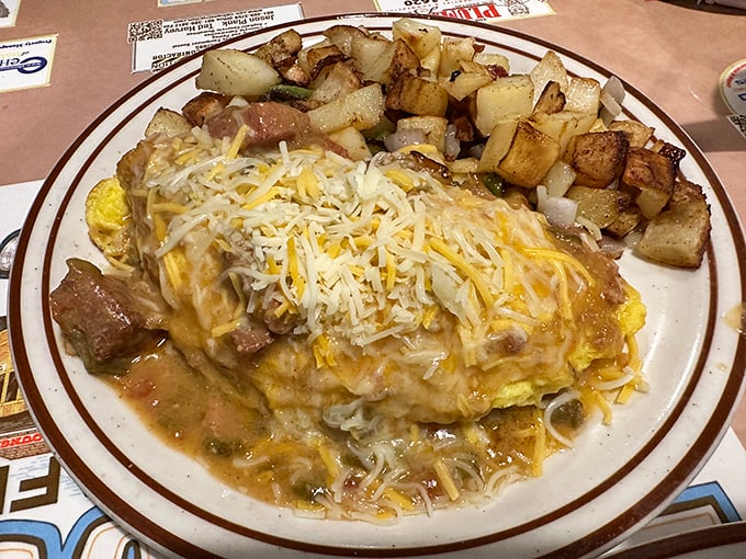 This isn't just an omelet&mdash;it's a cheese-covered monument to morning indulgence, with those perfectly crispy home fries playing the essential supporting role.