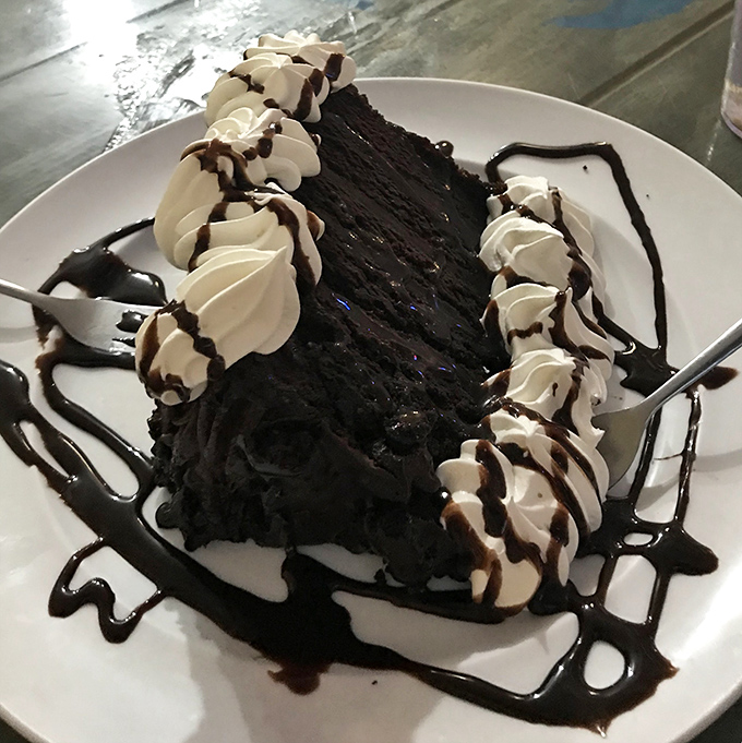 Chocolate cake so decadent it should require a permission slip, topped with whipped cream swirls that dance across the plate.
