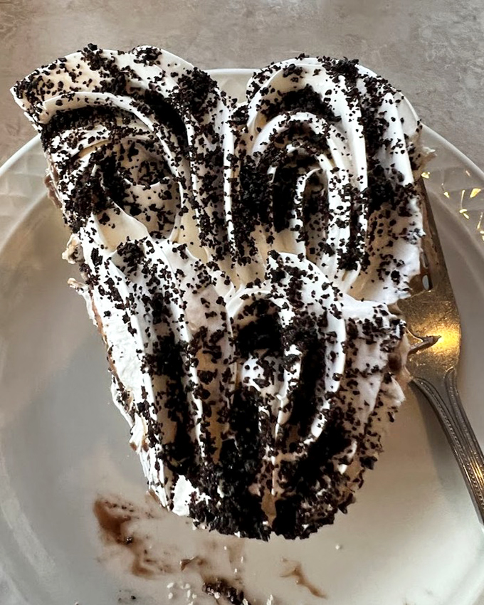 This isn't just chocolate cream pie; it's a towering monument to the art of dessert architecture, with cookie crumbles like delicious confetti celebrating your good decision.