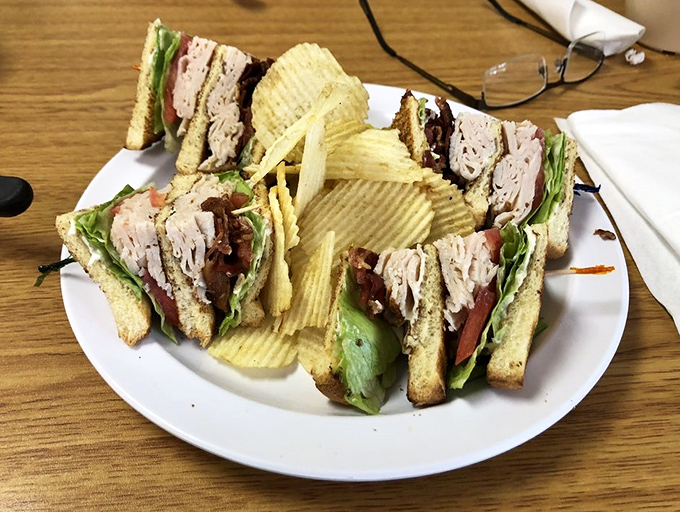 This club sandwich isn't just stacked—it's architectural genius. Layers of flavor skyscraping toward deliciousness, with potato chips standing guard around the perimeter.
