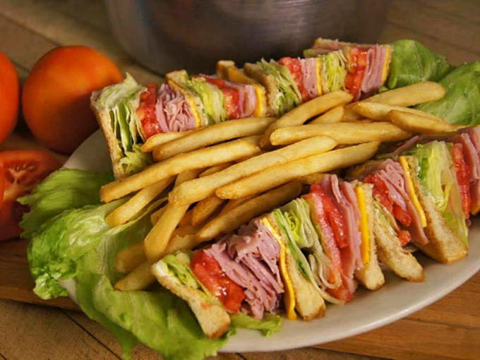 The club sandwich&mdash;that architectural marvel of deli meat, fresh vegetables, and toasted bread&mdash;stands tall with a fortress of golden fries as its loyal guards.