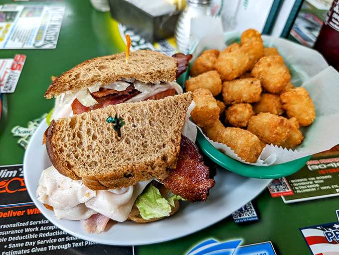 The legendary club sandwich in all its triple-decker glory, flanked by tater tots that look like they've achieved the perfect crunch factor.