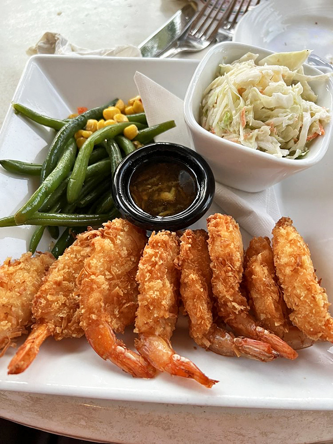 Crispy coconut shrimp lined up like delicious soldiers, accompanied by fresh green beans, sweet corn, and house-made coleslaw&mdash;a Florida beach meal that demands no apologies.
