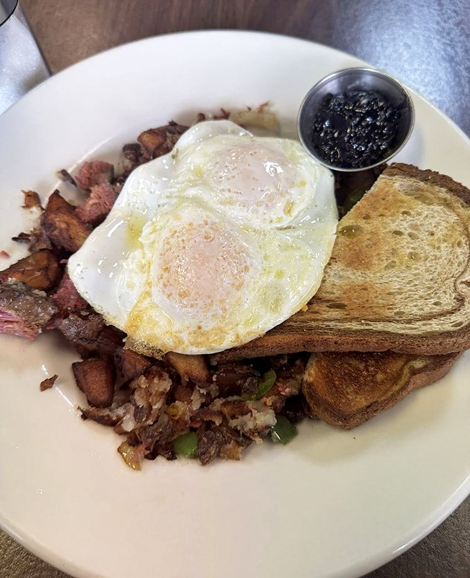 Breakfast nirvana: perfectly sunny-side-up eggs crowning a mountain of corned beef hash with toast standing by for yolk-sopping duty.