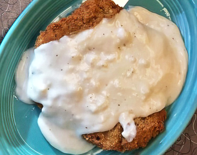 Country fried steak swimming in creamy gravy—the kind of breakfast that makes you want to take a nap by noon.