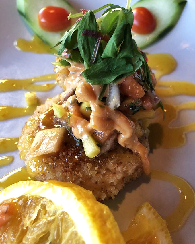 The crab cake that launched a thousand road trips. Golden-crisp exterior giving way to sweet crabmeat, with sauce artfully drizzled like an edible Jackson Pollock.