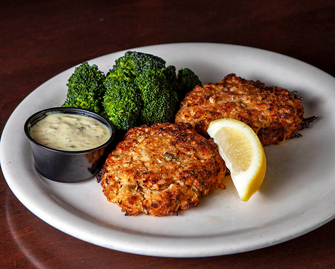 Golden-brown crab cakes with a side of steamed broccoli and house sauce—proof that simple food done right is culinary poetry.