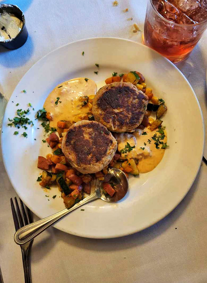 Golden-brown crab cakes nestled on a bed of colorful vegetables. Comfort food that's dressed for a night on the town.