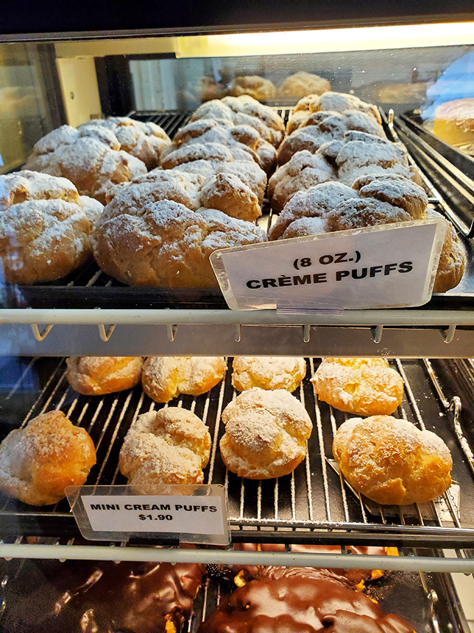 Cr&egrave;me puffs dusted with powdered sugar await their destiny. These cloudlike confections shatter delicately, revealing a vanilla cream interior that dreams are made of.