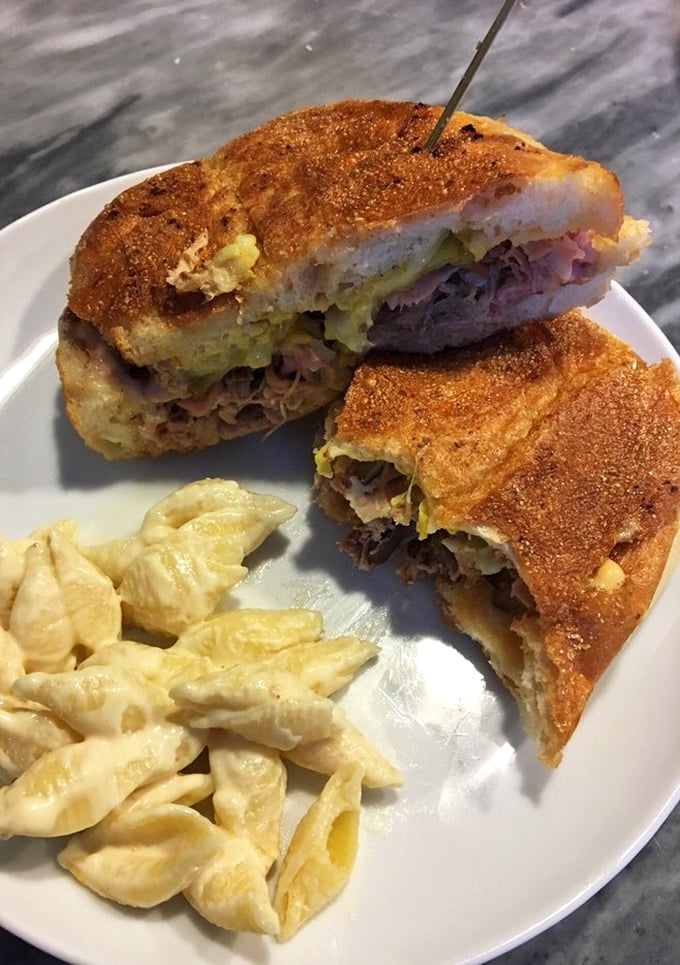 The Cuban sandwich, cut to reveal its inner secrets – a cross-section of harmony where pork, ham, and pickles find their perfect rhythm.