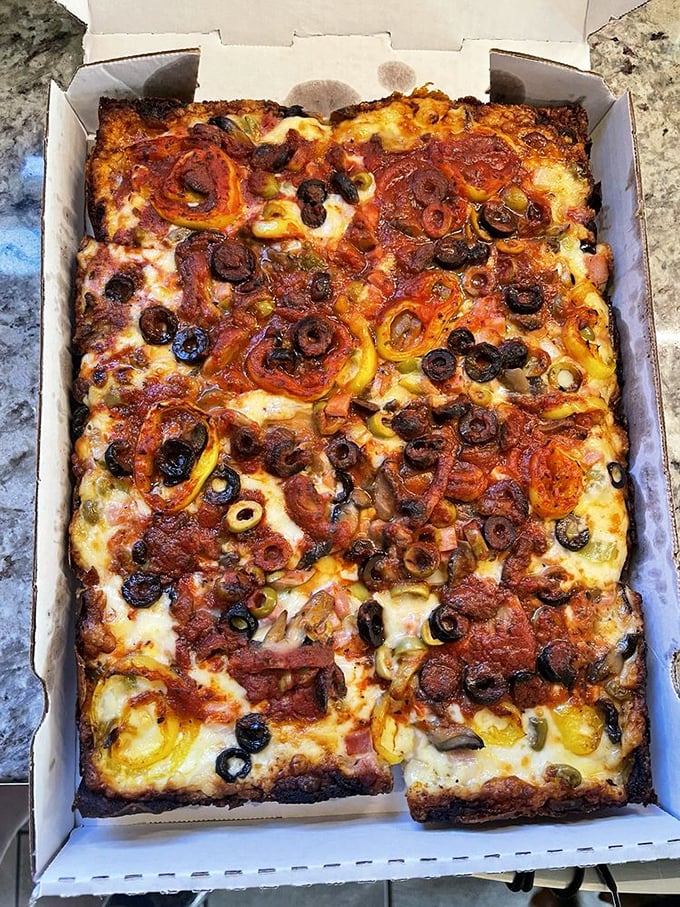 The holy trinity of Detroit pizza: crispy bottom, fluffy middle, and those glorious burnt cheese edges that should be illegal in at least seven states.