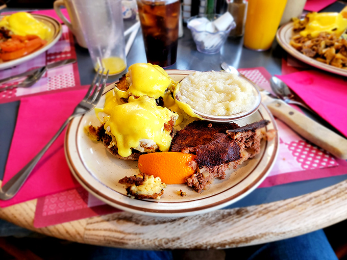 Eggs Benedict done right – a sunshine-yellow hollandaise cascading over perfectly poached eggs, with a side of creamy grits for good measure.