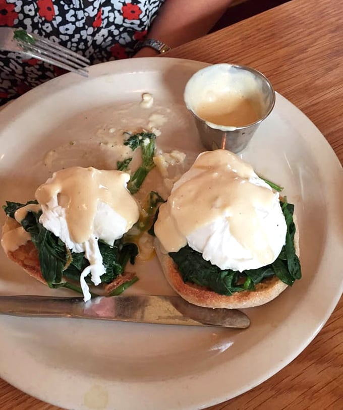 Poached eggs perched like culinary royalty on their spinach throne, hollandaise flowing like liquid sunshine below.