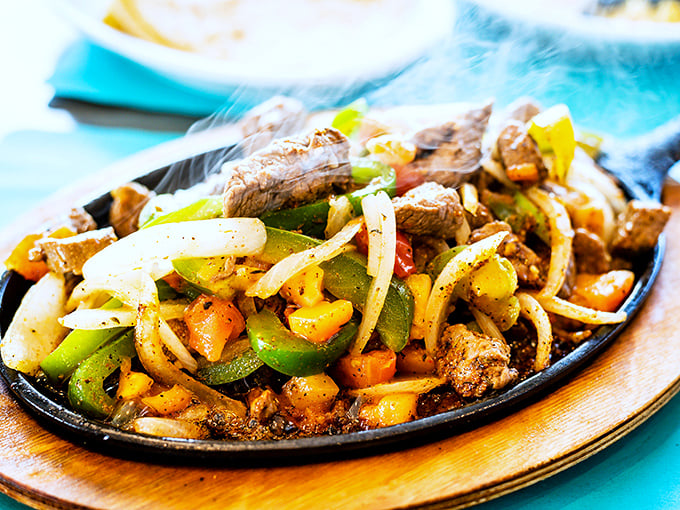 Sizzling fajitas that announce their arrival with theatrical flair—a symphony of steam, spice, and vegetables dancing with tender steak.