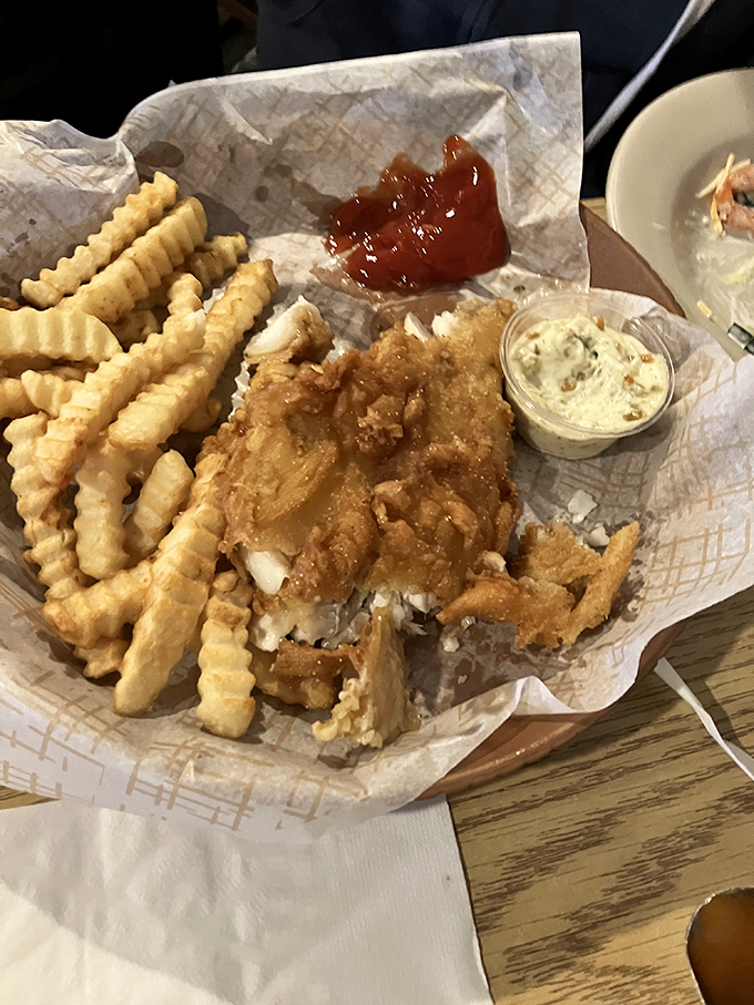 The fish and chips arrive like crispy golden treasures on a map of wax paper. That tartar sauce? The X that marks the spot.