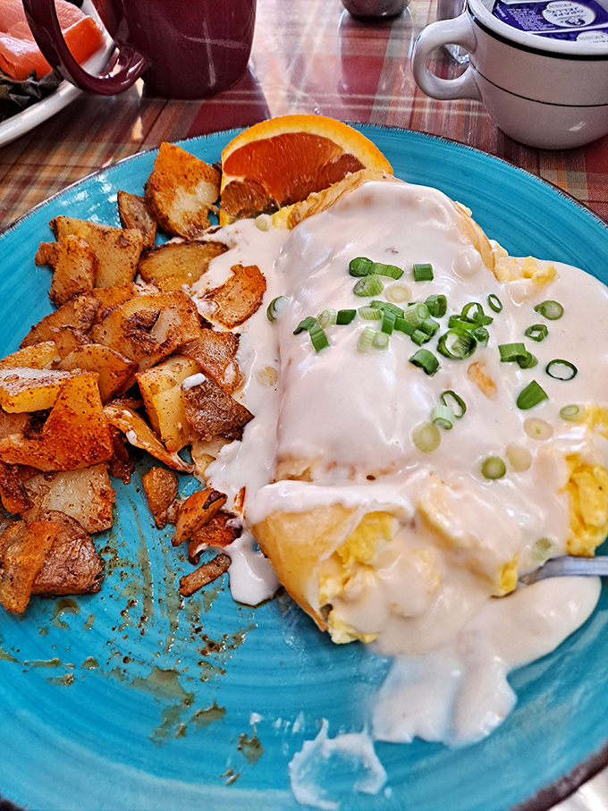 Breakfast nirvana: creamy eggs smothered in sauce, home fries with that perfect crisp-tender balance, and a slice of orange for when your conscience calls.
