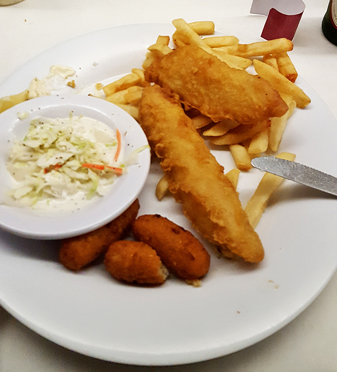 Fried fish so perfectly golden it belongs in Fort Knox, served with the holy trinity of seafood sides: hush puppies, fries, and creamy coleslaw.