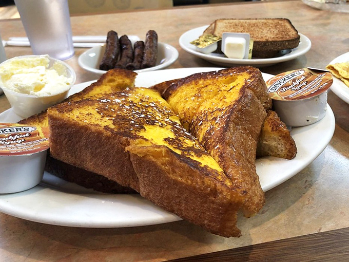 French toast that's achieved that perfect golden-brown alchemy, flanked by breakfast meats standing at attention like delicious sentries.