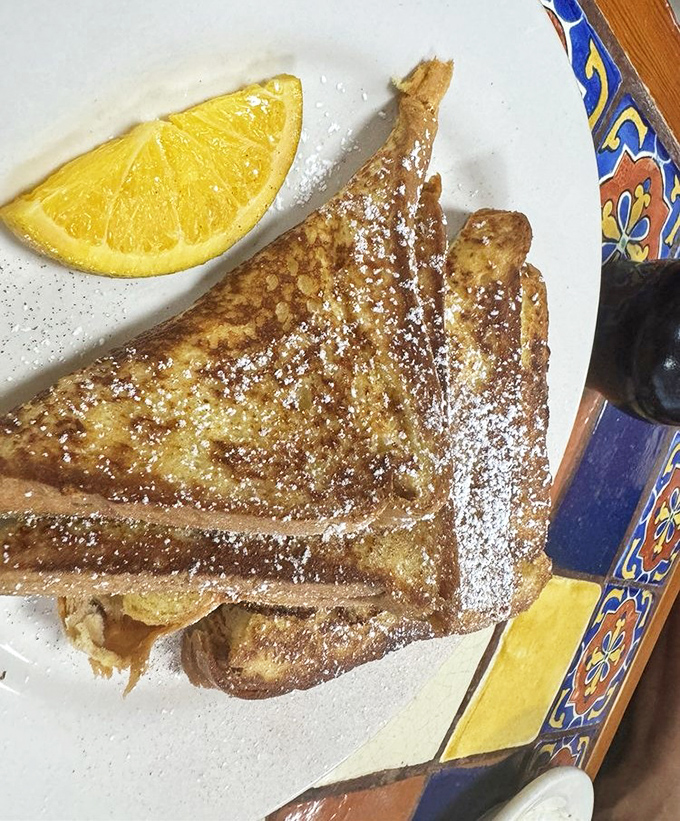 French toast dusted with powdered sugar and served with a citrus slice—breakfast's answer to "Why can't every morning feel this special?"