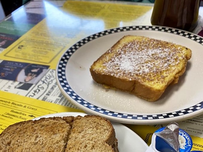 French toast dusted with powdered sugar sits regally on a checkered plate &ndash; simple perfection that doesn't need to show off.