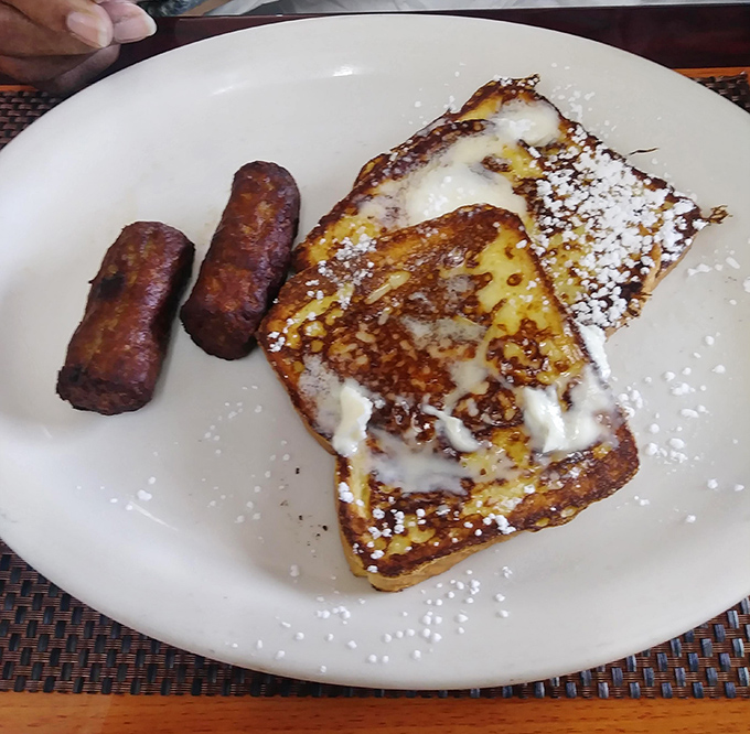Behold the crown jewel: golden-fried chicken perched atop a Belgian waffle throne, dusted with powdered sugar like freshly fallen snow.