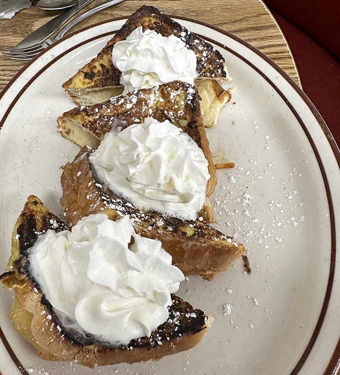 French toast that's crossed the line from breakfast to dessert, with whipped cream islands melting into powdered sugar snowdrifts. Diet starts tomorrow, folks.